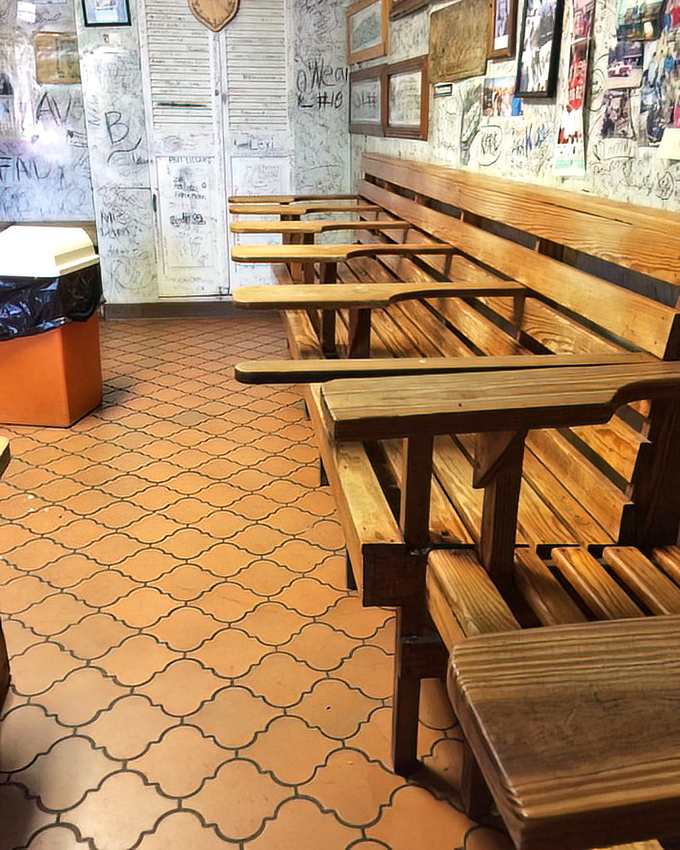 The dining area's wooden benches and graffiti-covered walls tell stories of visitors past—each signature a testament to burgers worth remembering.