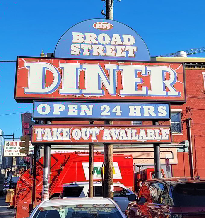 The vibrant red and blue signage announces "OPEN 24 HRS" to night owls and early birds alike—a democratic institution serving breakfast democracy to all.