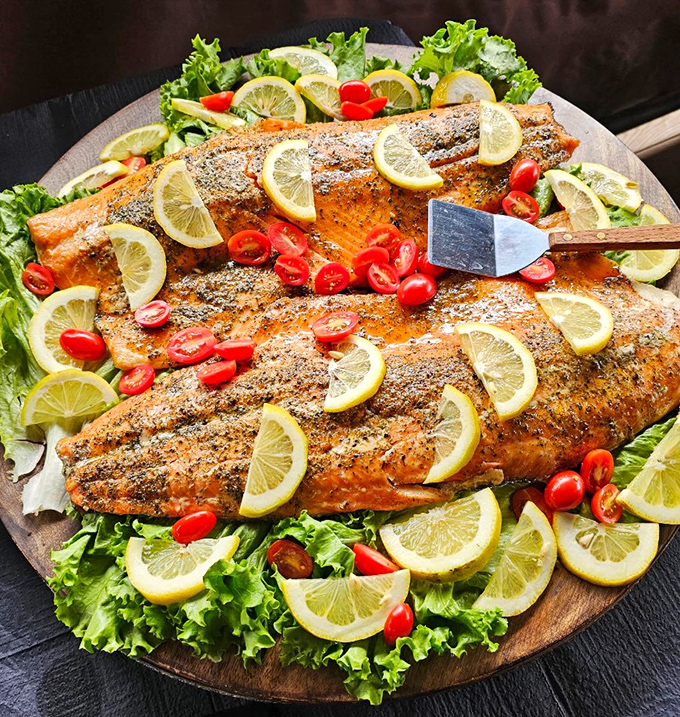 This isn't just salmon – it's an aquatic masterpiece, dressed for success with lemon slices and cherry tomatoes on its bed of greens.