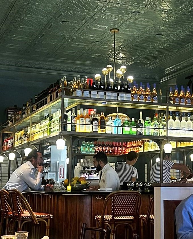 The ornate bar display isn't just storage—it's theater. Bottles backlit like precious artifacts, promising libations that transform an ordinary evening into something memorable.