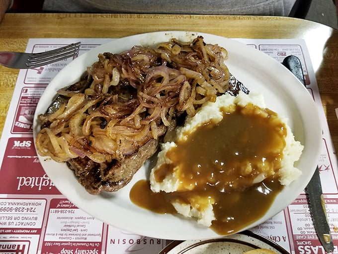 A steak topped with caramelized onions alongside mashed potatoes drowning in gravy. This plate doesn't just satisfy hunger – it creates happiness.