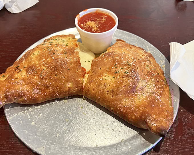 Golden-brown, perfectly baked stromboli with marinara for dipping – a handheld feast that somehow improves on the already perfect pizza concept.