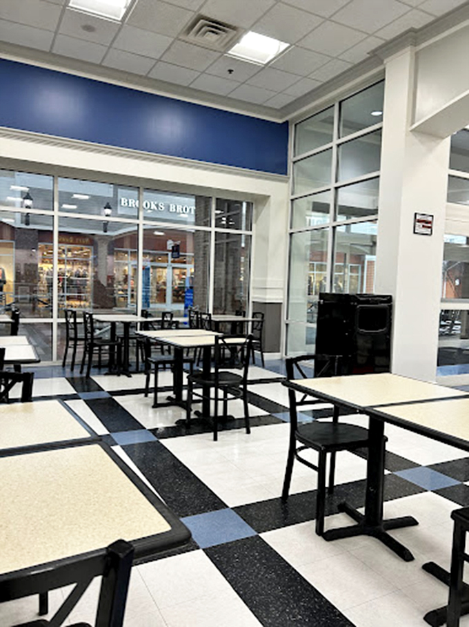 The food court's chess-board floor and minimalist seating stand ready for shoppers to refuel before embarking on the second leg of their retail marathon.