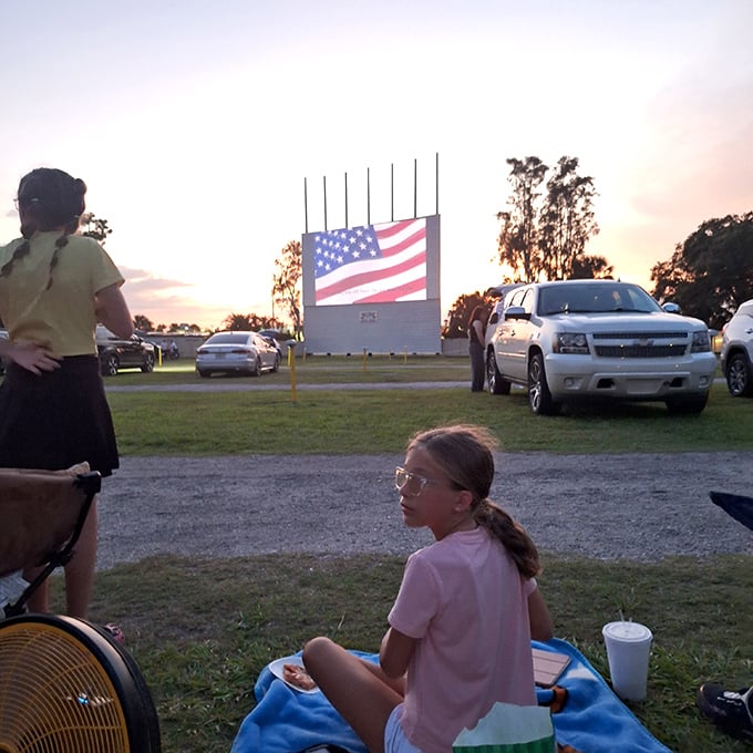 Blankets spread on grass, cups balanced carefully—this is how memories are made. The American flag onscreen adds a touch of heartland nostalgia.