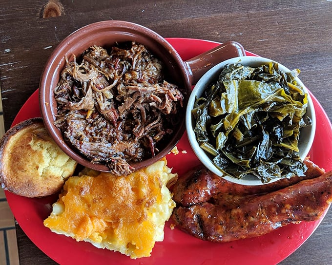 A barbecue plate that tells the whole story—pulled pork, collards, cornbread, and mac and cheese forming a perfect Southern quartet.