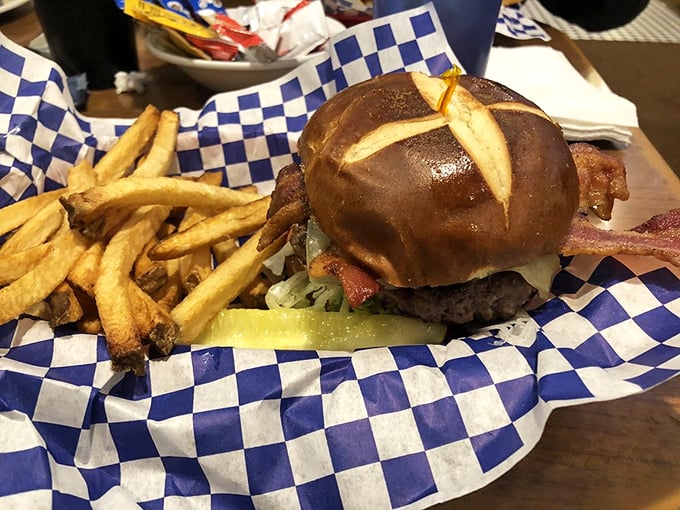 A burger that requires both hands and a strategy – served on a pretzel bun with fries that deserve their own fan club.