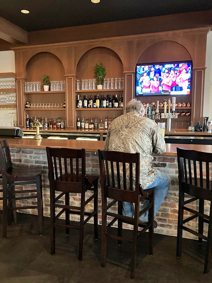 The bar area showcases an impressive collection of spirits, particularly bourbons, arranged like treasures behind the brick-fronted counter.