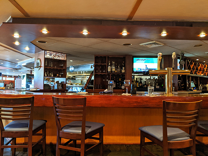A bar that promises stories with every sip – where polished wood meets brass fixtures and every stool offers a front-row seat to mixology magic.