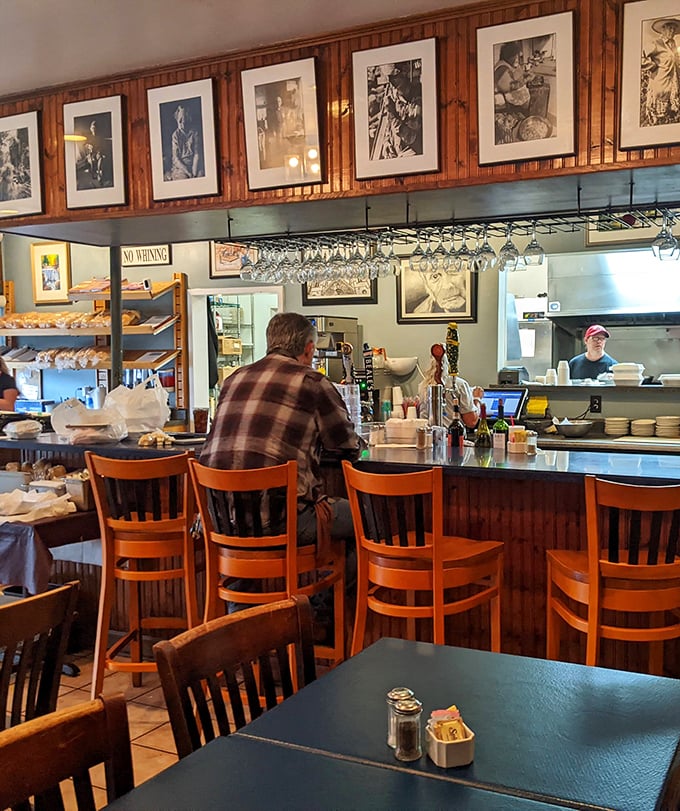 The bar area—where framed photographs tell stories and hanging wine glasses promise good decisions waiting to be made.