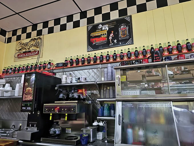 That lineup of vintage Coca-Cola bottles isn't just decoration—it's a timeline of American refreshment watching over the diner like fizzy sentinels. 