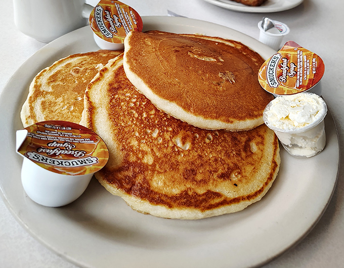 Pancakes that look like they were painted by Norman Rockwell himself—golden, fluffy, and waiting patiently for their maple bath.