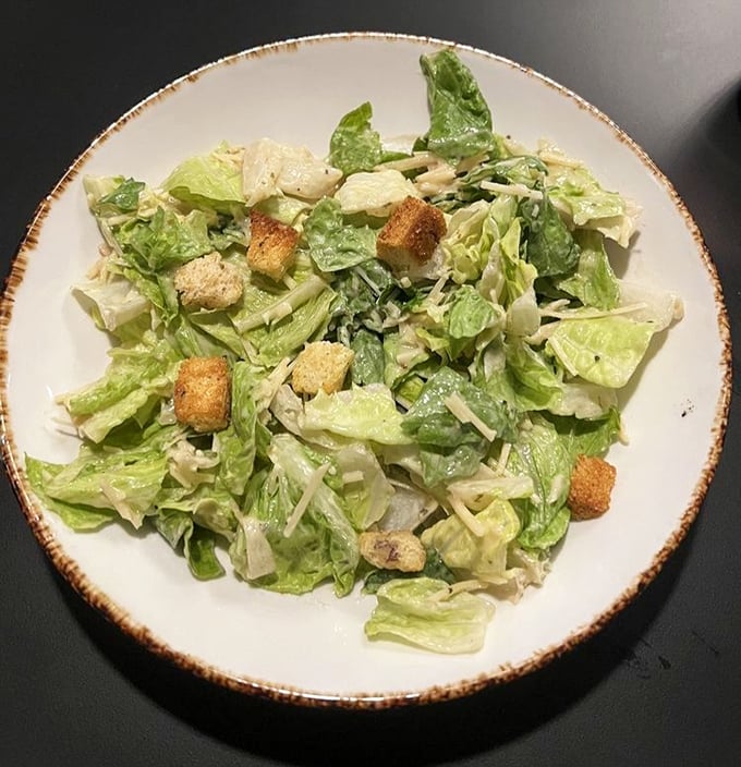 A Caesar salad that knows its role – to provide the illusion of healthiness before the parade of protein arrives. Those croutons didn't come from a box.
