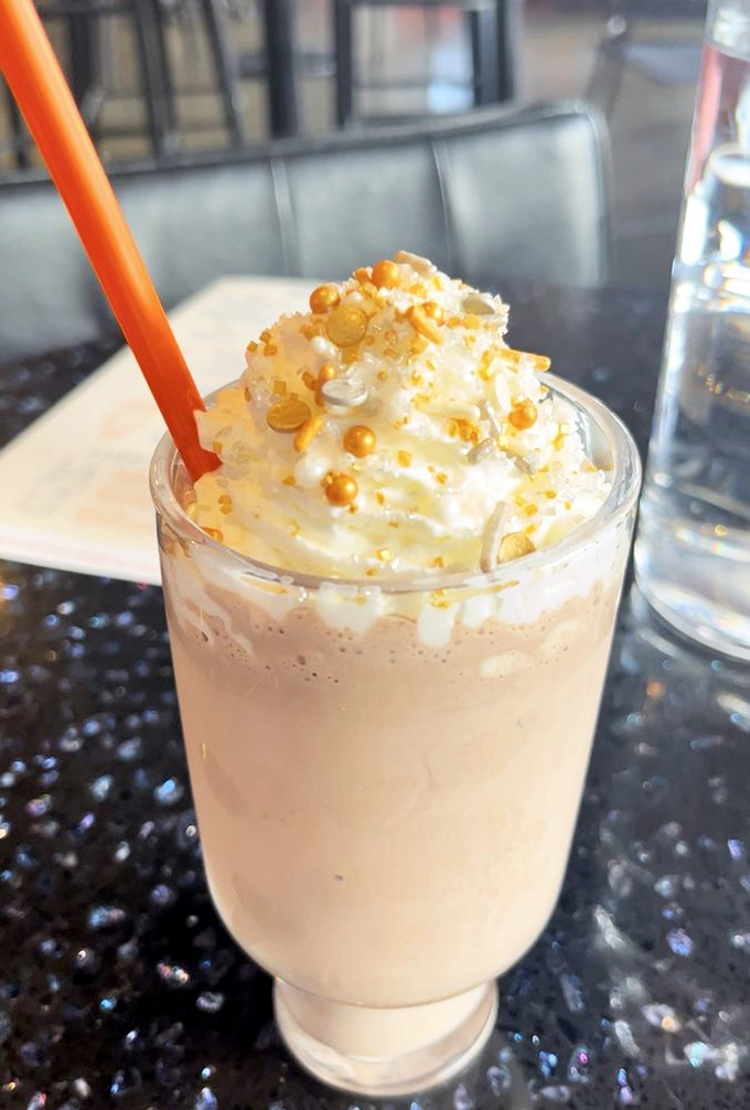 A milkshake topped with whipped cream and golden pearls. Drinking dessert never looked so celestial—or required such impressive straw strength.
