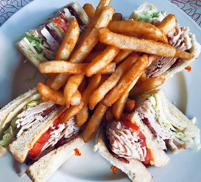 The club sandwich—America's architectural marvel—where layers of deliciousness are held together by the humble toothpick, humanity's greatest invention.