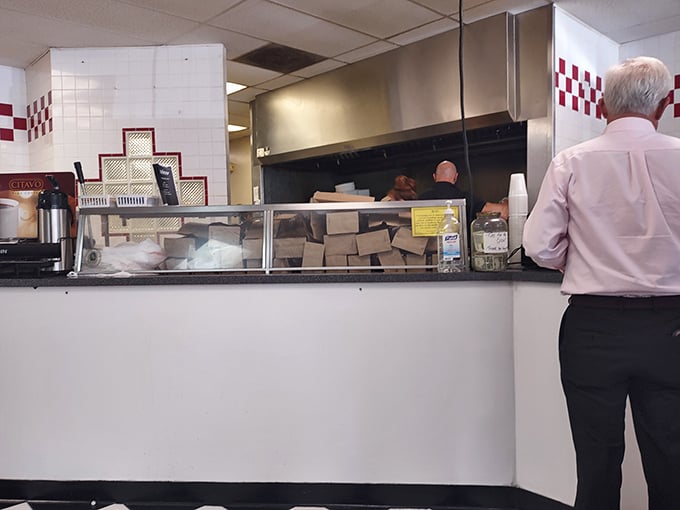Where sandwich magic happens—the counter view offers a glimpse into the choreographed dance of deli professionals at work.