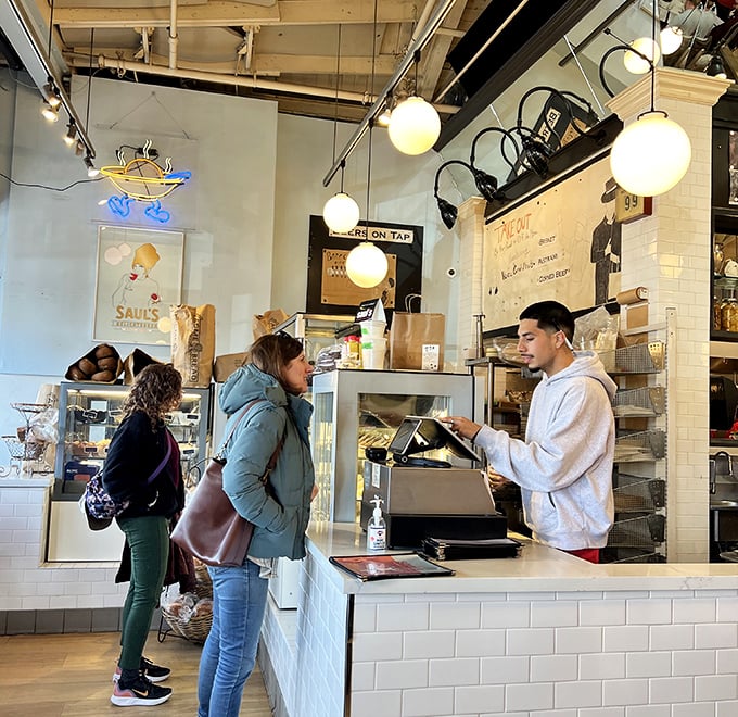 The counter where deli dreams come true, one order at a time. Notice nobody's checking their phones—the food demands full attention.