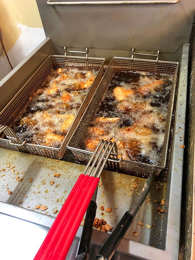 A behind-the-scenes glimpse at where the magic happens—bubbling oil transforming ordinary chicken into extraordinary culinary memories that keep locals coming back.