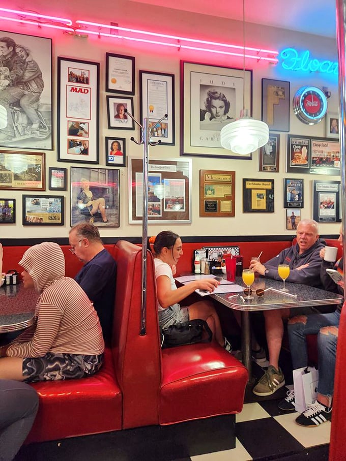 Red booths under neon lights—where strangers become neighbors and everyone's connected by the universal language of "pass the syrup, please."