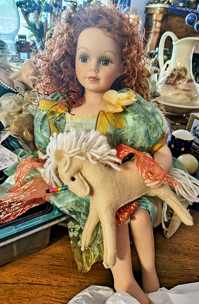 Porcelain perfection meets childhood nostalgia in this red-haired doll, complete with felt unicorn companion—someone's cherished memory.