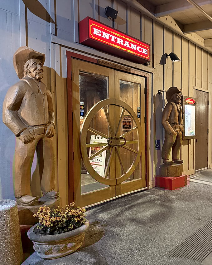 Wooden cowboys stand eternal guard at the entrance, silently judging if you're hungry enough to deserve what awaits inside. The wagon wheel door adds authentic charm.