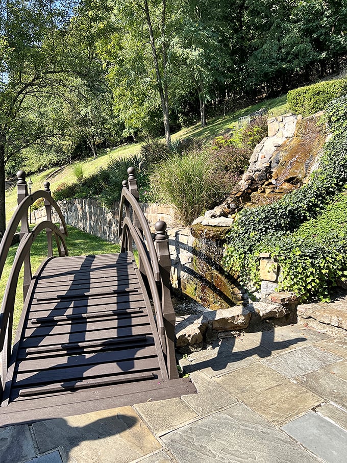 A footbridge worthy of poetry leads visitors across a gentle stream—no moat monsters included, though I'm sure they were considered.