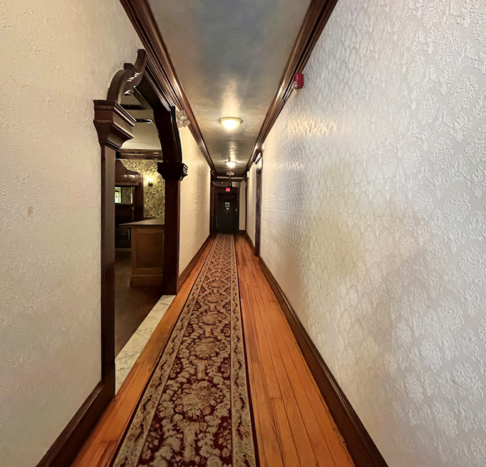 The hallway's vintage charm hints at the building's history—wooden floors and ornate runner creating a pathway to dining satisfaction.