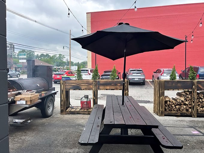 Picnic tables, shade umbrellas, and the smoker nearby—this isn't just outdoor seating, it's barbecue's natural habitat in its purest form.