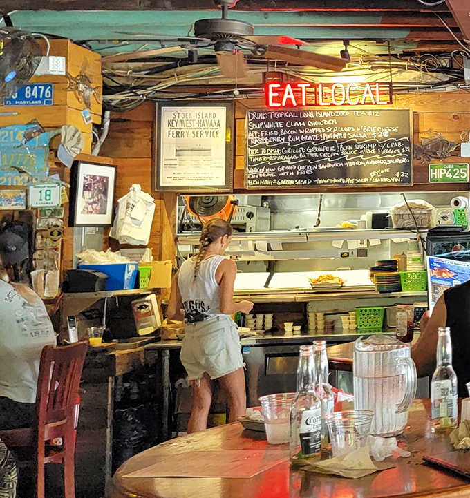 The "EAT LOCAL" sign isn't just decoration—it's the Hogfish philosophy illuminated in neon, with a chalkboard menu showcasing the day's freshest catches.
