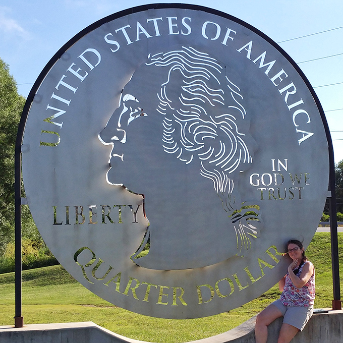 "I'm worth exactly 25 cents more in this photo!" Summer visitors find shade and smiles beside this gleaming roadside attraction.