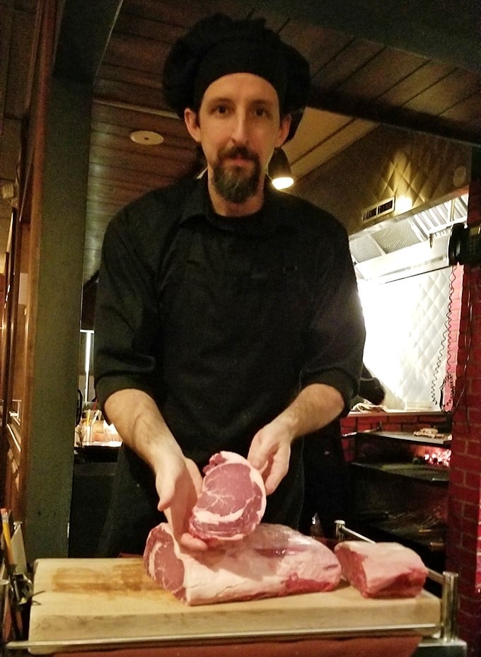 The chef selects each cut with expert precision—these hands understand that great steak begins long before it meets the grill.
