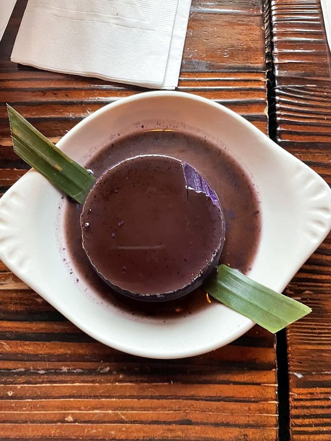 This isn't just dessert, it's a cultural handshake—ube flan that bridges continents with its silky purple perfection and banana leaf garnish.