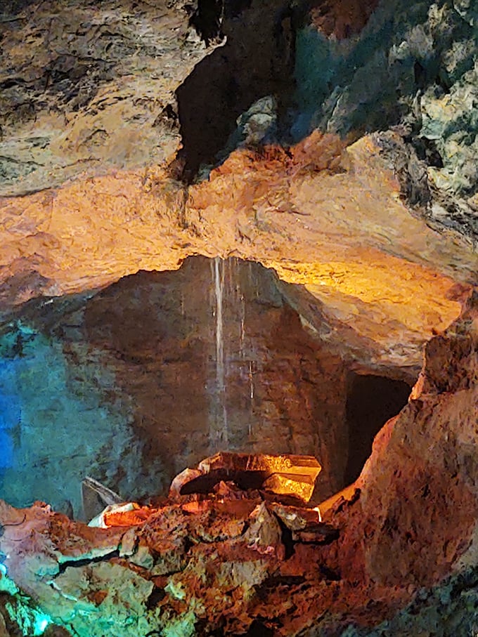 The underground waterfall creates its own spotlight moment. Water and light dance together in this geological theater, performing a show millions of years in the making.