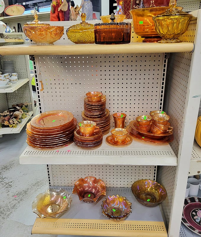 Amber carnival glass gleams like liquid sunshine on the shelf—each piece whispering stories of elegant dinner parties from decades past.