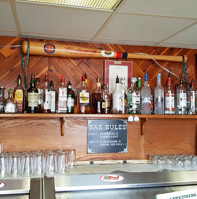 Behind the bar, a Cubs bat watches over spirits and glassware. The "Bartender is Always Right" sign tells you everything about Heinnies' sense of humor.