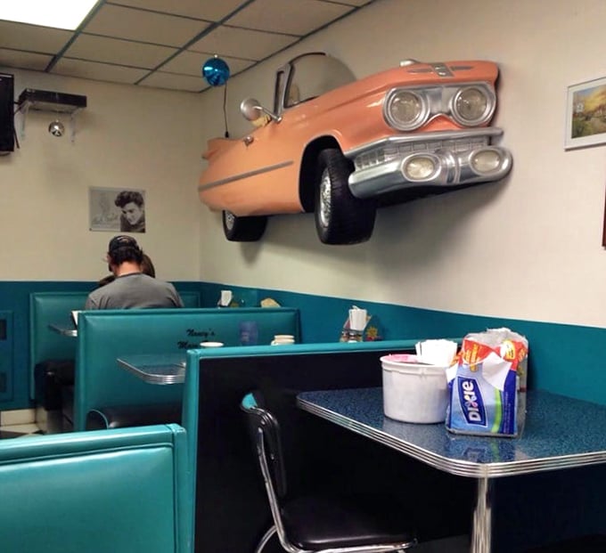 That vintage car bursting through the wall isn't just decoration—it's a metaphor for how this diner crashes through the barrier between past and present.
