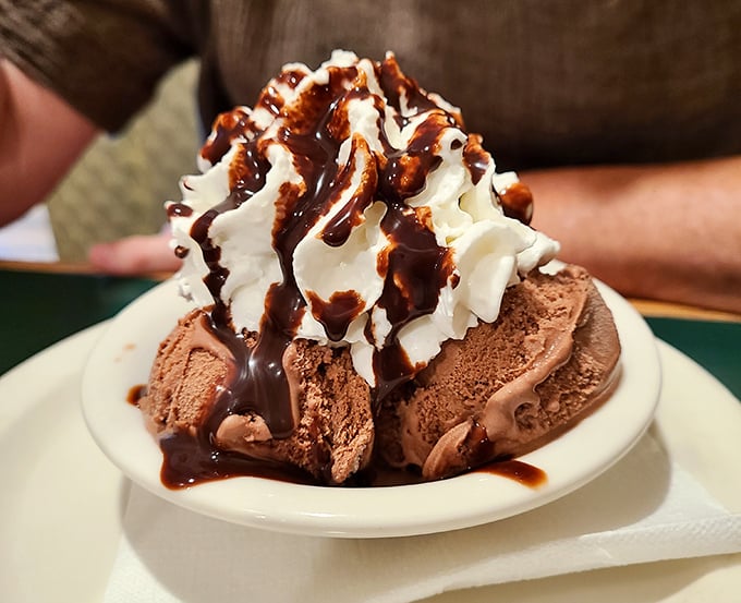 Ice cream elevated to art form—chocolate scoops crowned with whipped cream and hot fudge in a dessert that demands to be savored slowly.