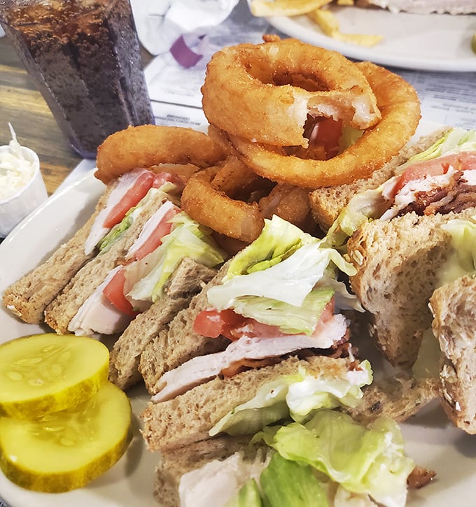 The club sandwich—America's greatest contribution to lunch—stacked high with the promise of satisfaction and those essential crispy onion rings.