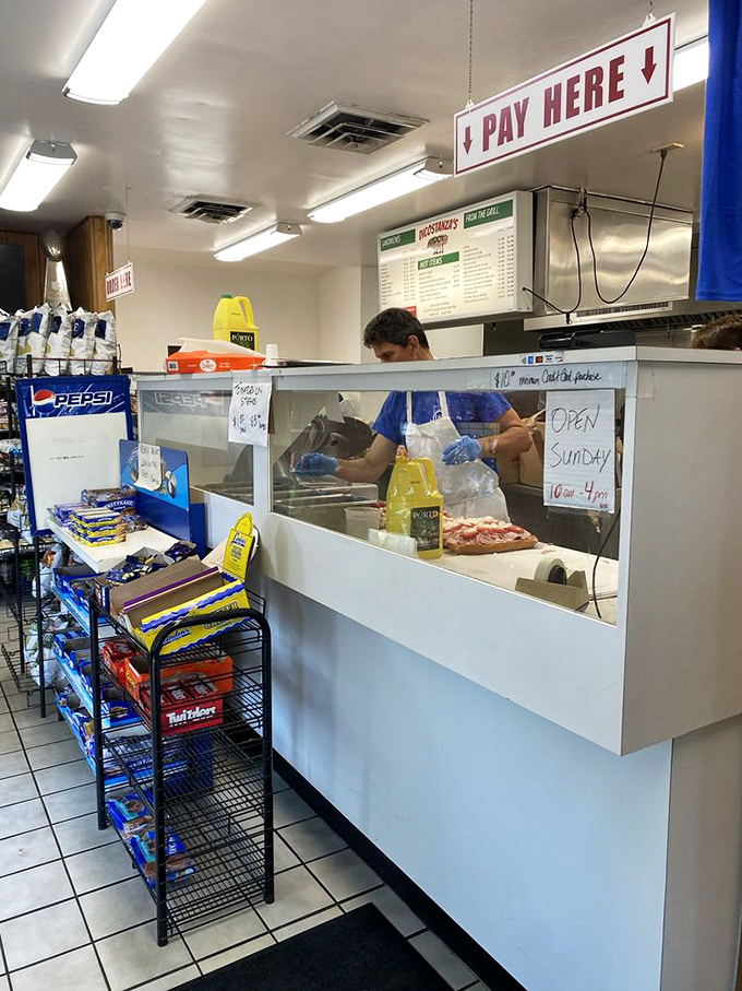 The "PAY HERE" sign hangs above sandwich artisans at work. That plexiglass isn't separating you from them—it's protecting their craft.