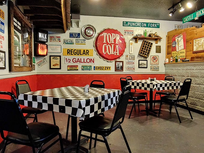 The dining area's red accents and checkered tablecloths pop against vintage automotive memorabilia—eating here is time travel with toast.