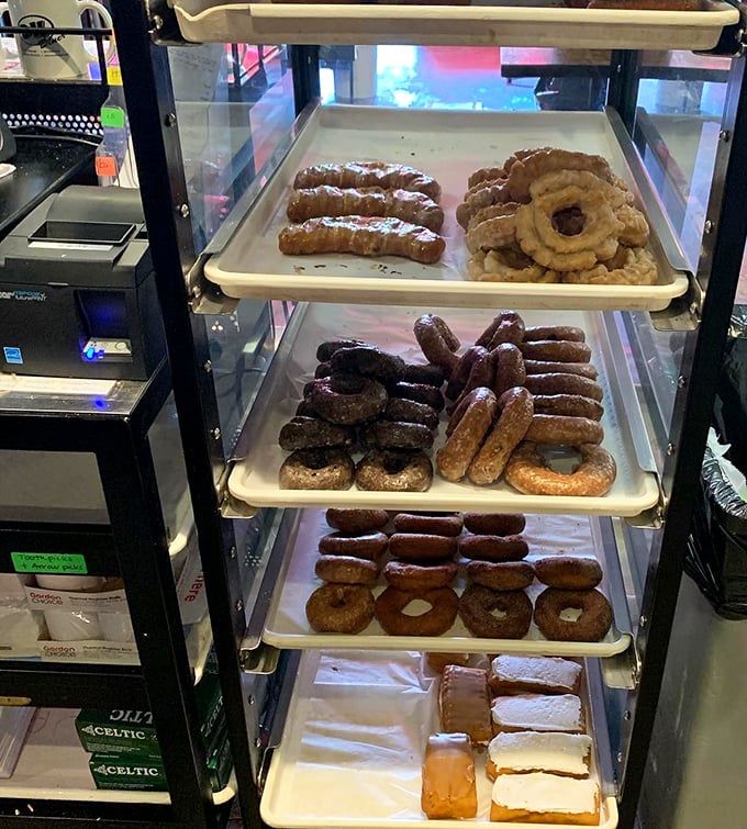 The donut display case—a glass-enclosed museum of breakfast art where glazed, frosted, and filled masterpieces await their moment of glory. 