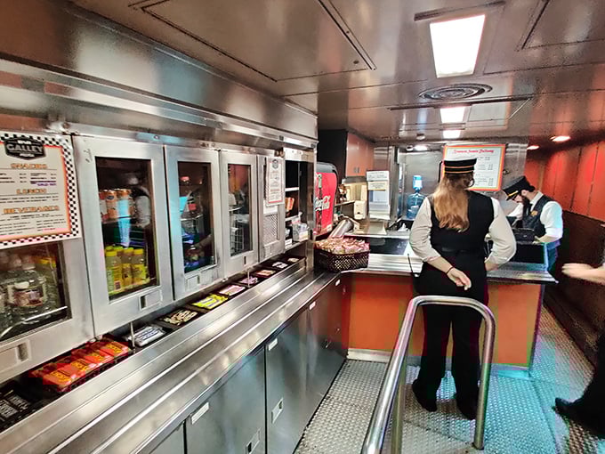 The snack car attendant stands ready in classic uniform. Because hunger waits for no trestle, and these views work up an appetite.