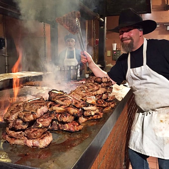 Where the magic happens: Mesquite smoke rises as steaks sizzle on the grill. The chef's smile says everything about the pride in his work.