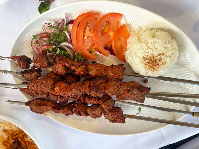 Perfectly grilled kebabs arrive with vibrant vegetables and aromatic rice—a simple yet profound reminder of why this cooking technique has endured for centuries.
