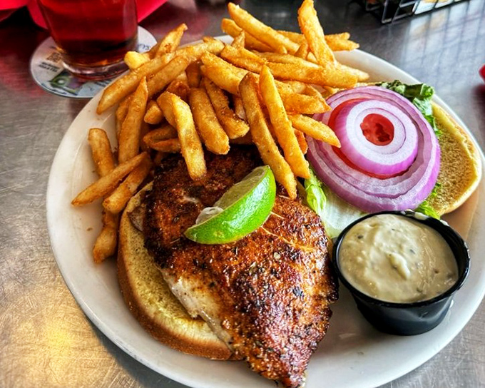 This blackened fish sandwich isn't messing around—crispy fries, tangy sauce, and a lime wedge standing by for emergency flavor deployment.