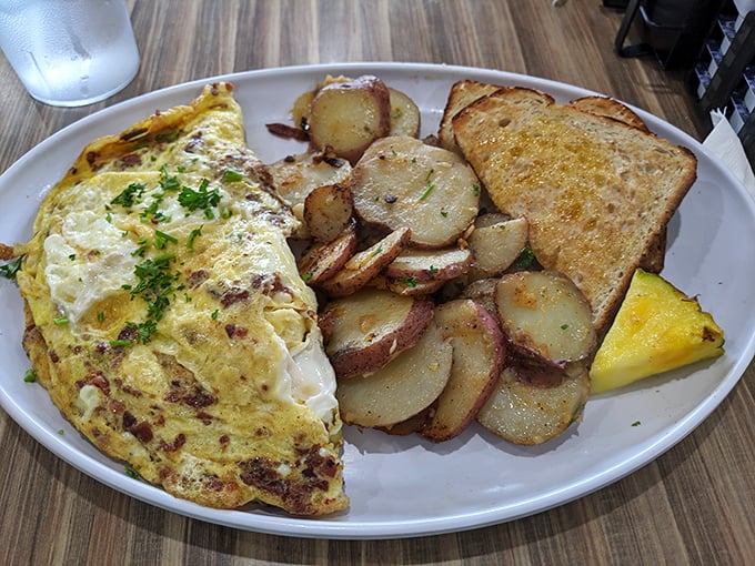 This omelet doesn't just sit on the plate—it lounges confidently beside golden home fries like it knows it's the star of the show.