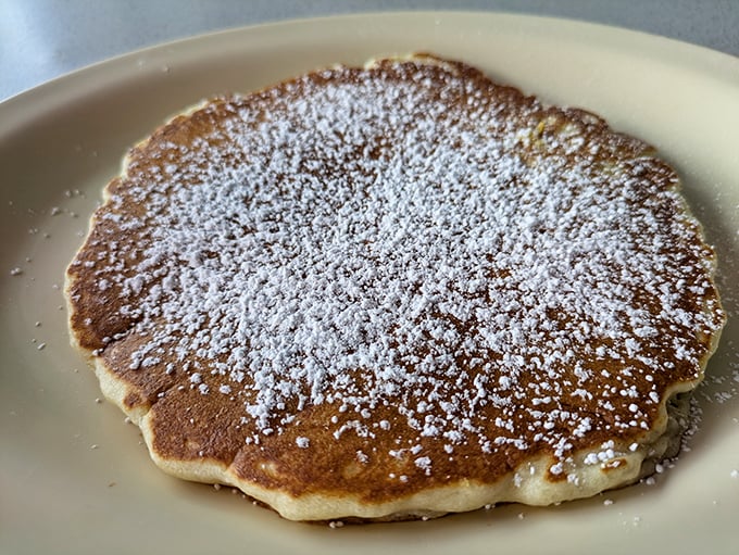 This pancake isn't just dusted with powdered sugar – it's wearing a delicate snowfall that transforms breakfast into an occasion.