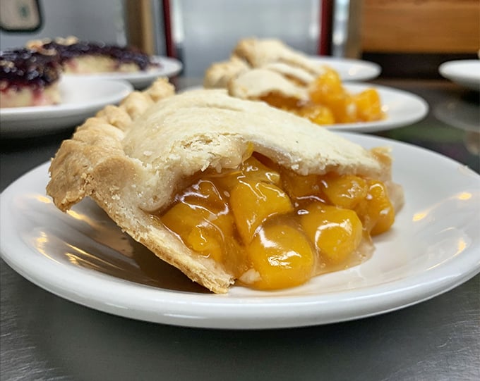 Peach pie that captures summer in every bite—flaky crust barely containing the sweet, juicy filling that's worth every sticky chin and happy sigh.