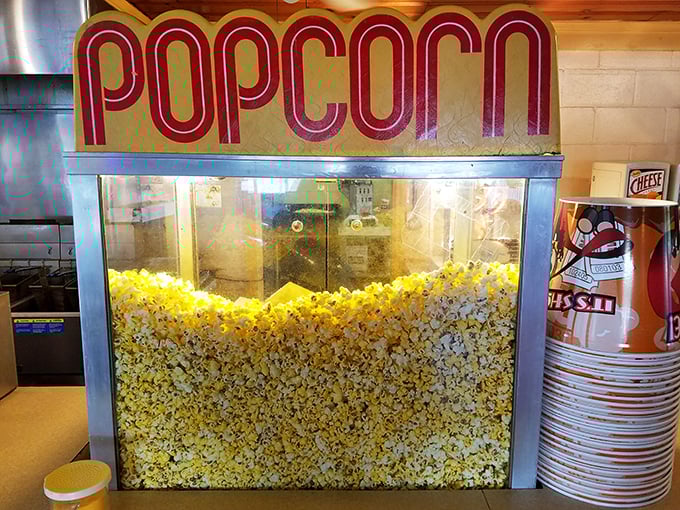 The popcorn machine—hypnotic in its golden abundance, promising that perfect combination of salt, butter, and nostalgia with every kernel.