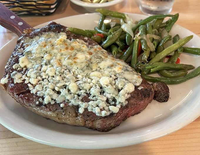 A ribeye topped with blue cheese that doesn't need your approval—it already knows how good it is. Those green beans provide the illusion of virtue.