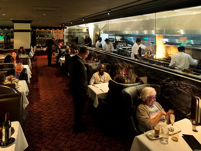 The dining room offers front-row seats to culinary theater, where flames leap and chefs orchestrate your dinner with the precision of symphony conductors.